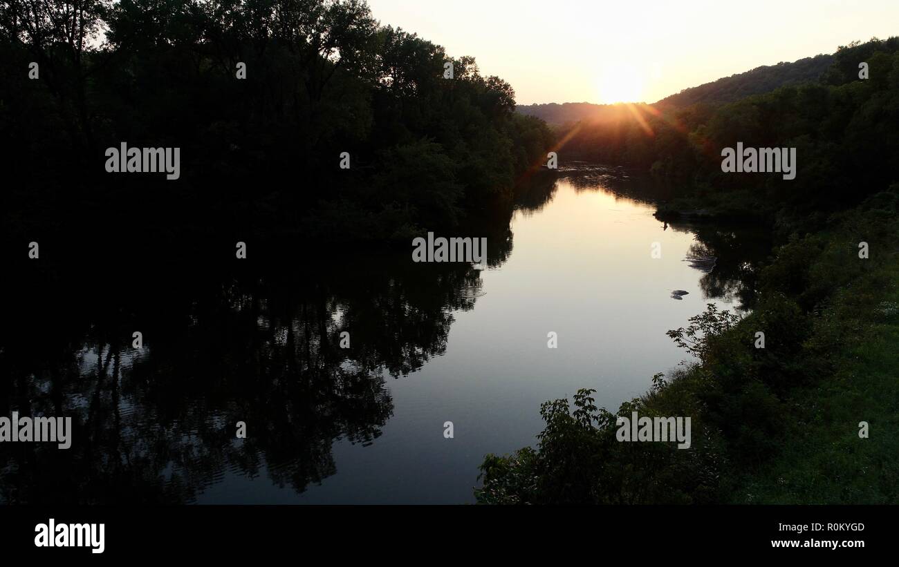 Aerial view of fisherman wading into calm Zumbro River at sunset, with ...