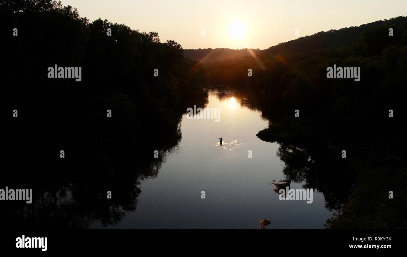 Aerial view of fisherman wading into calm Zumbro River at sunset, with ...
