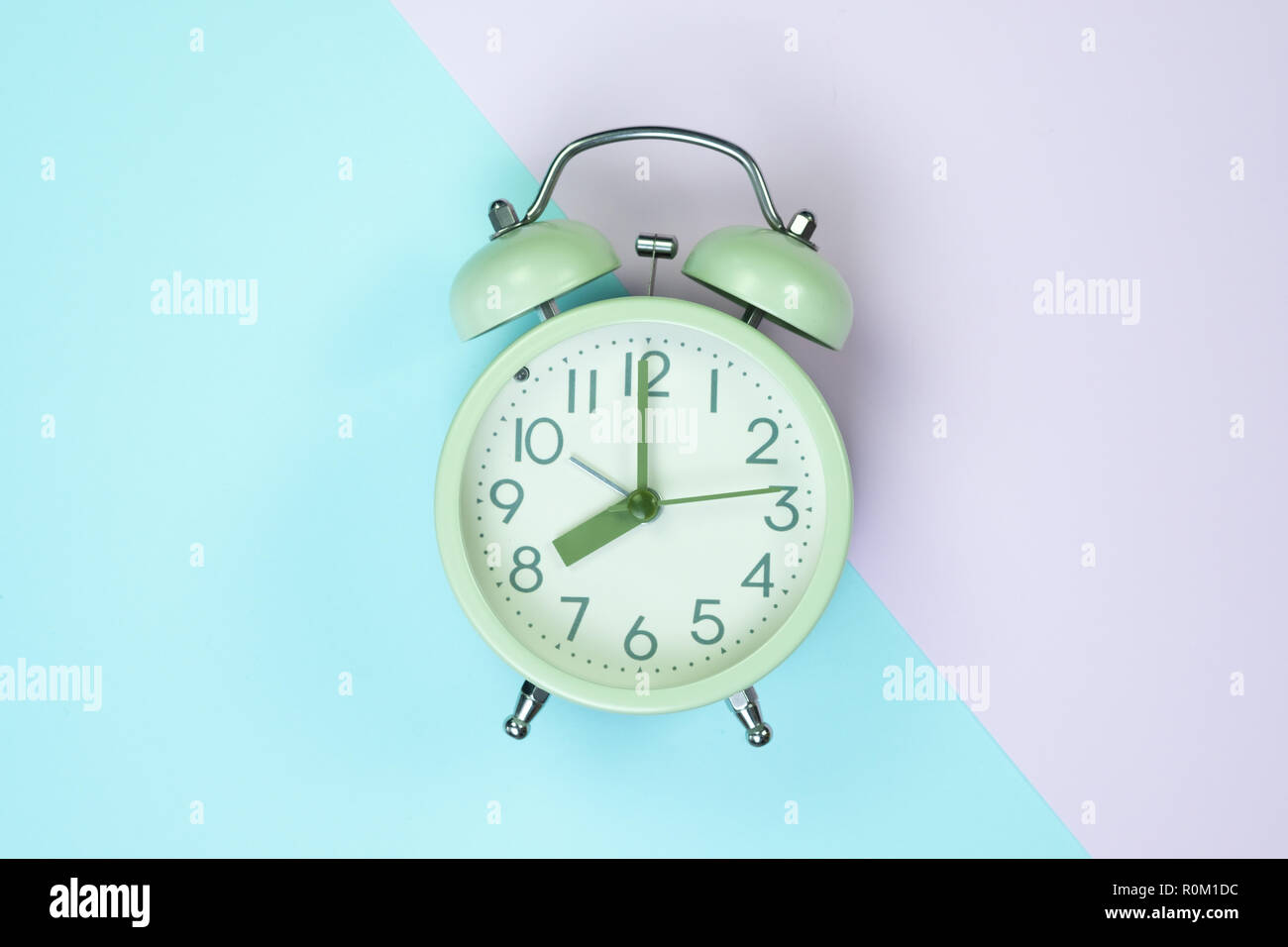 Flat lay vintage alarm clock on sweet pastel colored paper top view ...