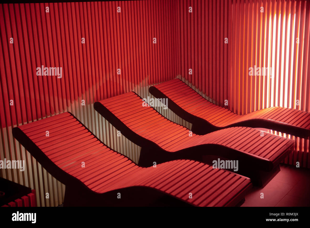 Red light colored empty sauna chairs Stock Photo - Alamy