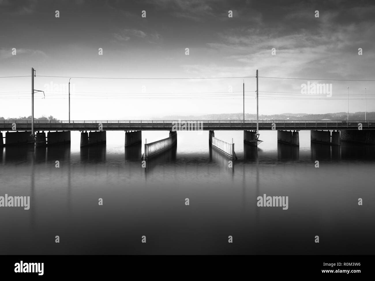 concrete bridge over water with a train line and road running parallel ...