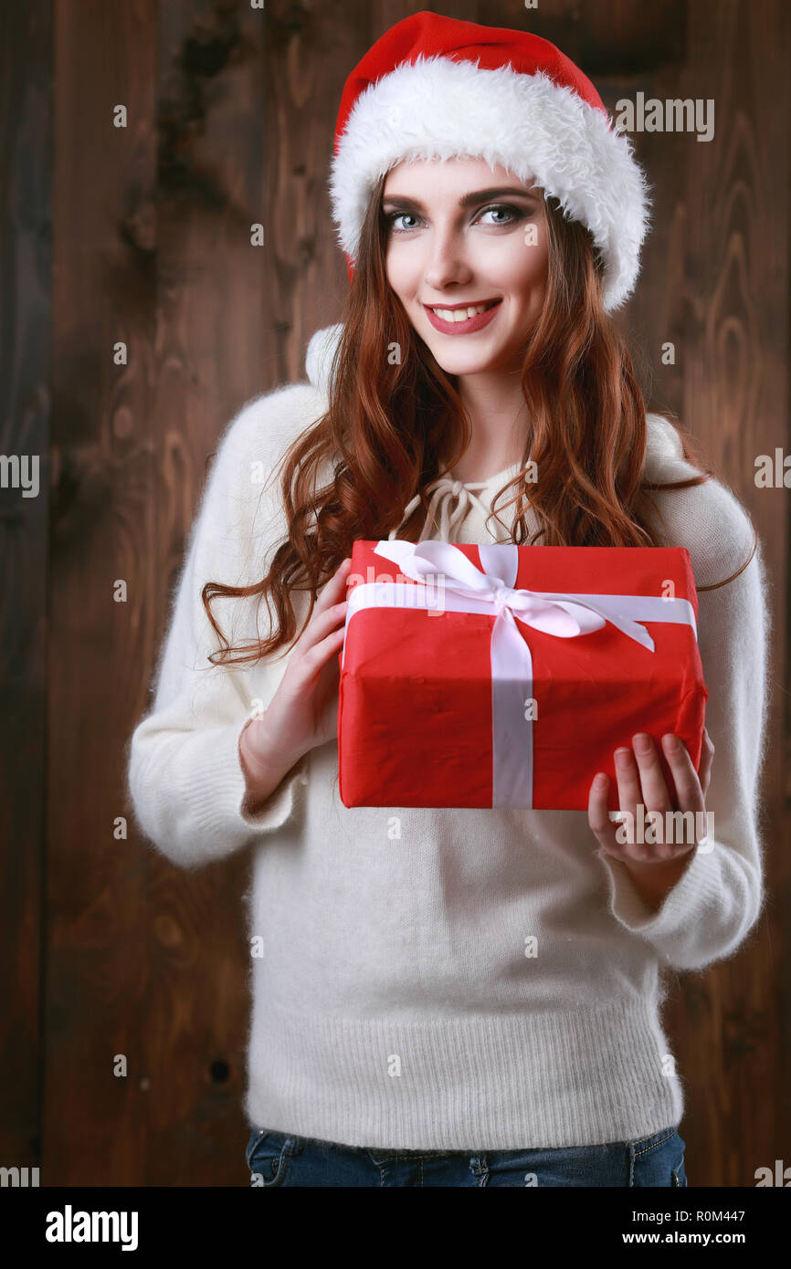Happy excited young woman in santa claus hat with gift box over gray ...