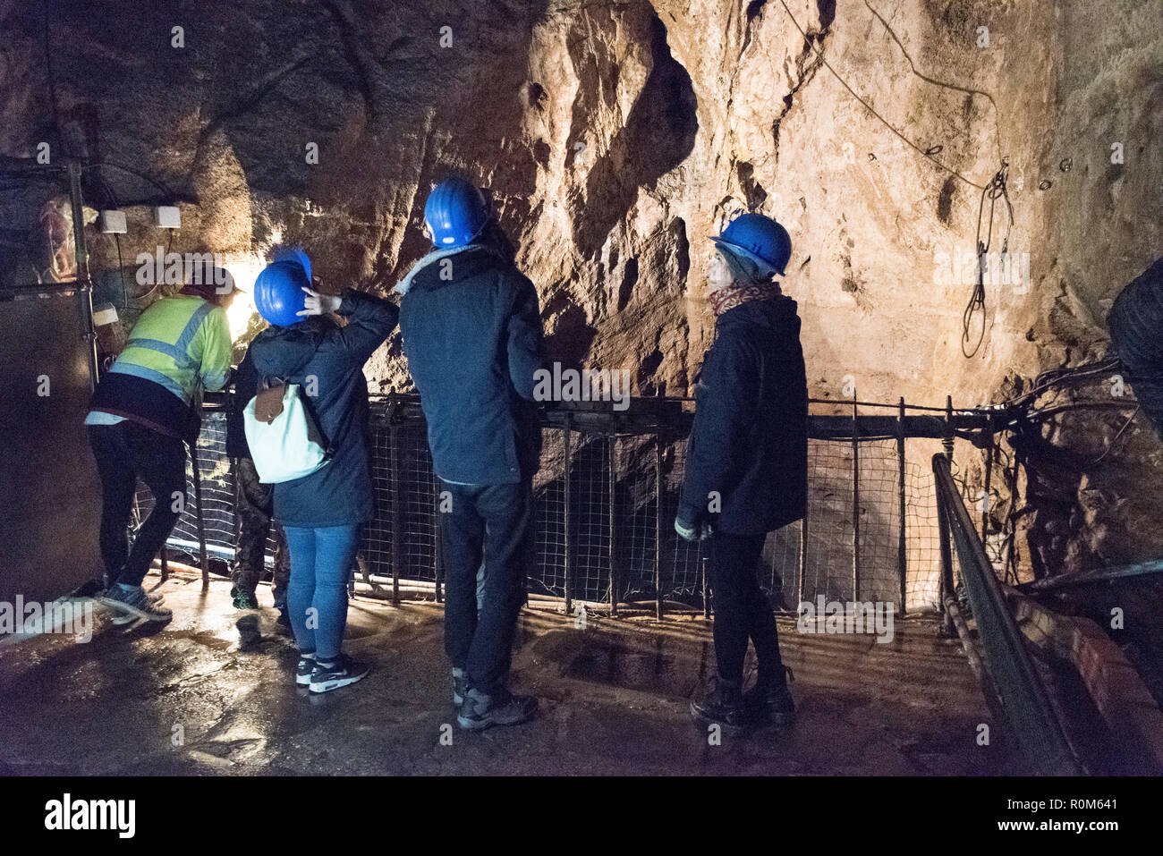 A group of visitors wearing safety helmets, peer down a 20 metres ...