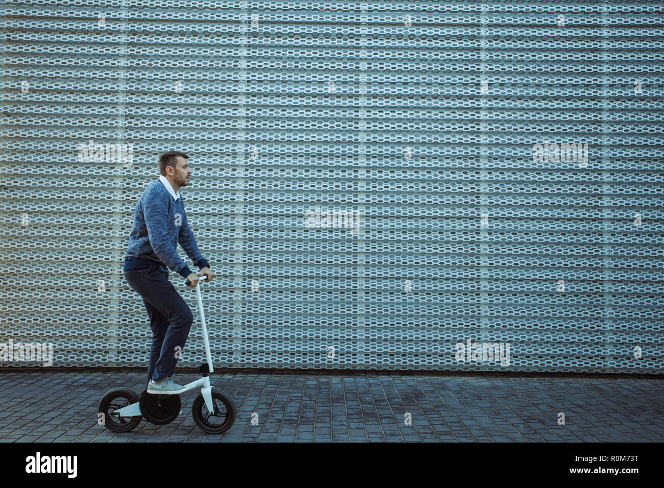 Side view of man pushing kick scooter while riding on beautiful ...