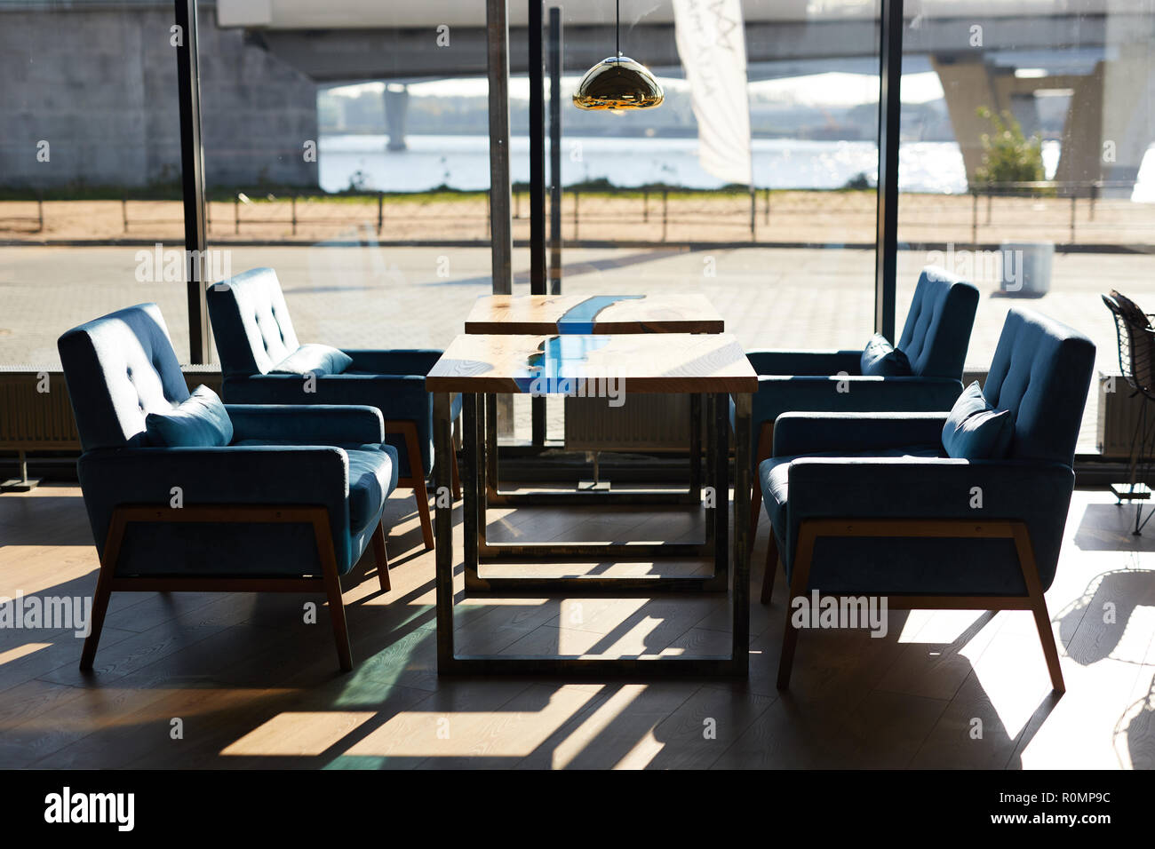 Two small tables and four chairs around and lamp hanging over with ...