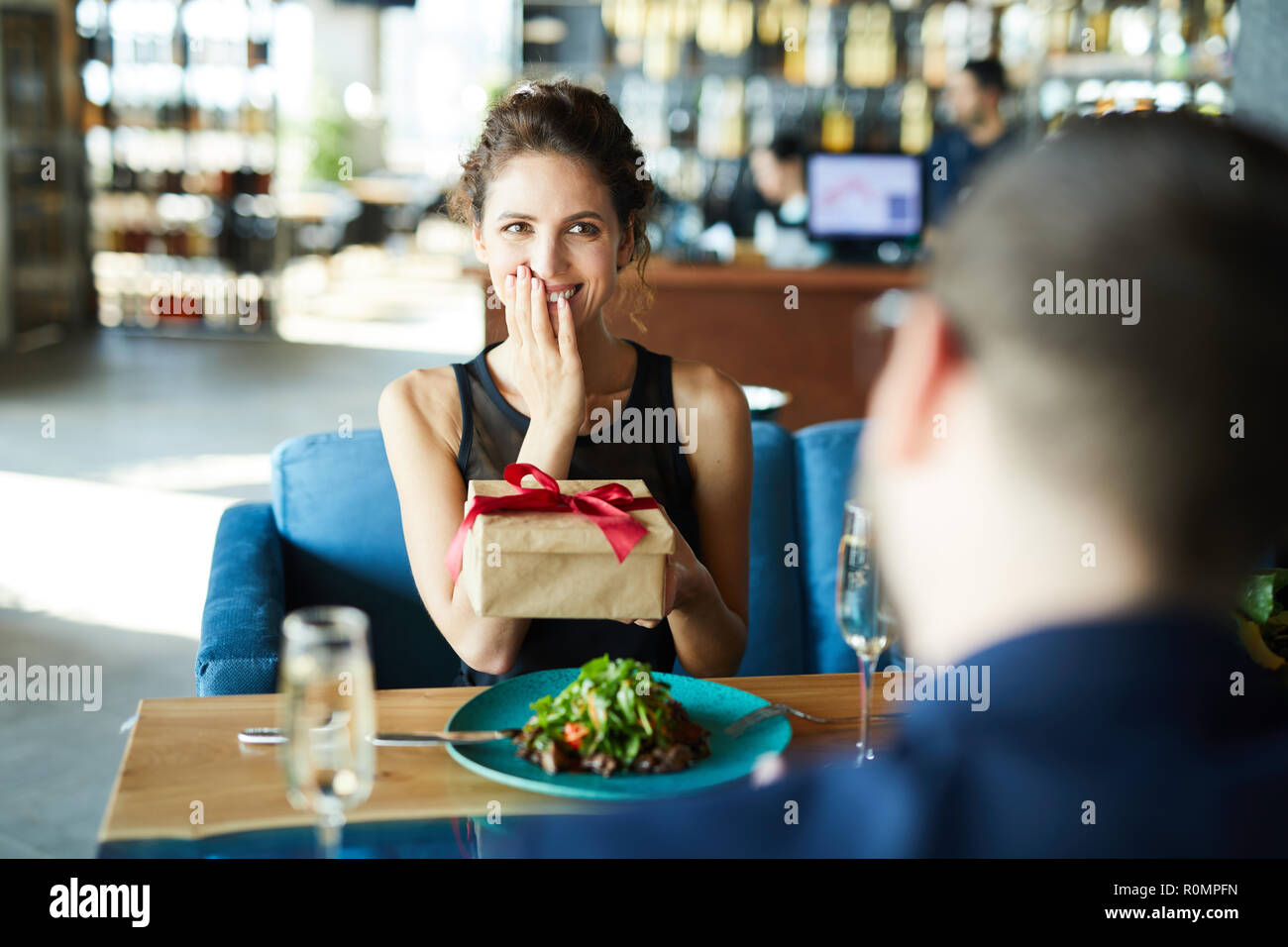 Young excited woman holding box with unexpected gift from her boyfriend ...