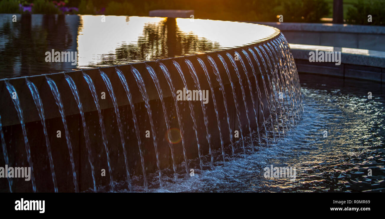 Reflections on the water of a fountain at sunset Stock Photo - Alamy