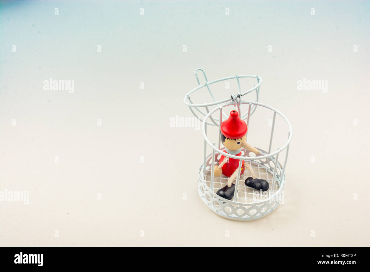 Metal cage and Little puppet pinocchio made of wood Stock Photo - Alamy