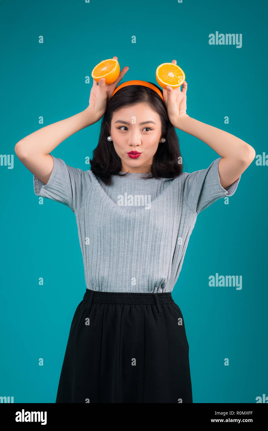 Healthy food. Smiling lovely pinup asian girl holding orange over blue ...