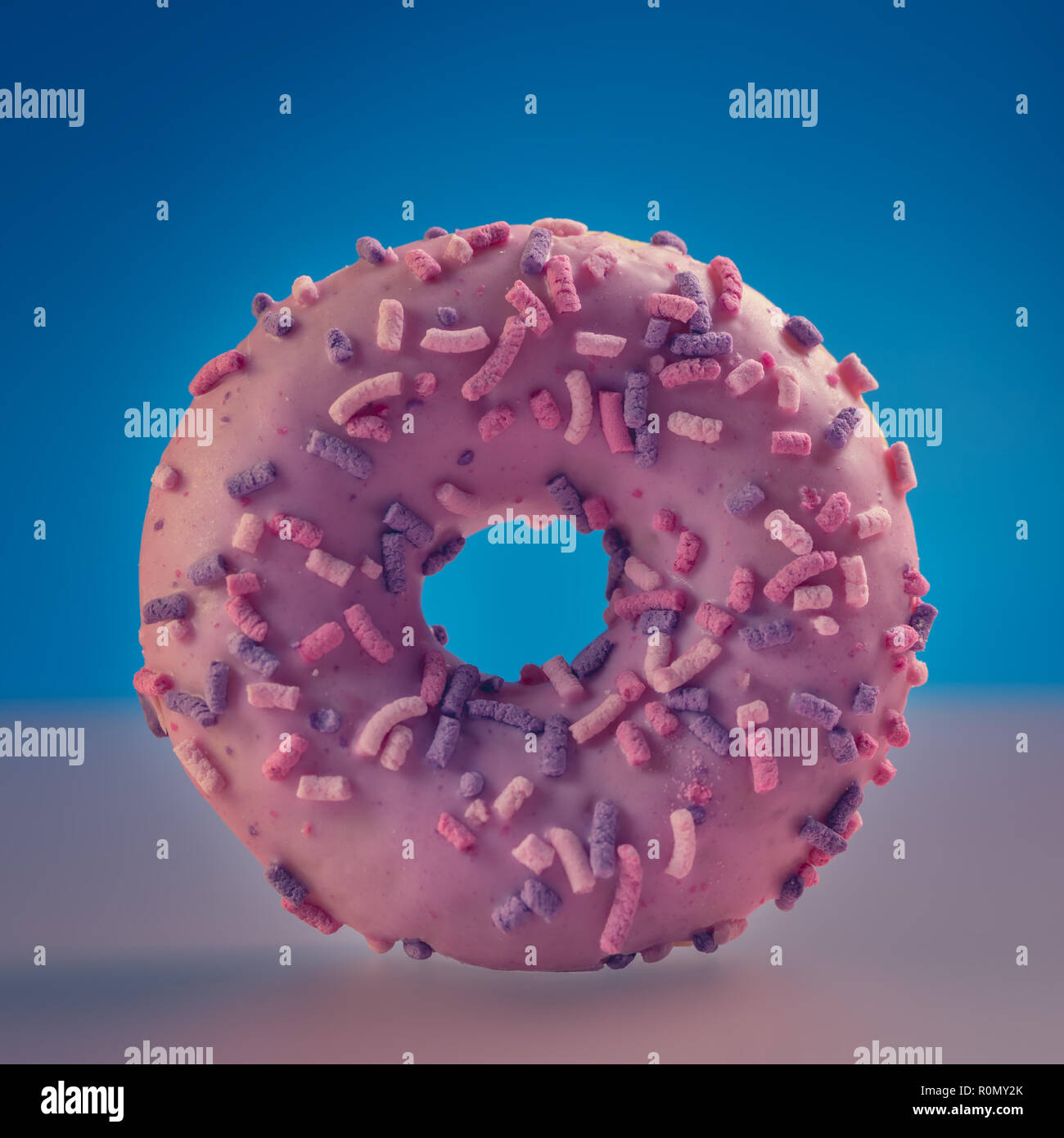 Single round donut on blue background Stock Photo - Alamy