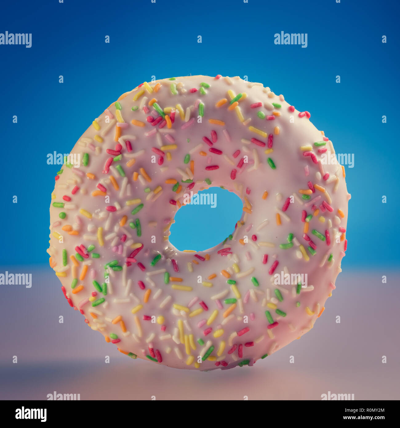 Single round donut on blue background Stock Photo - Alamy