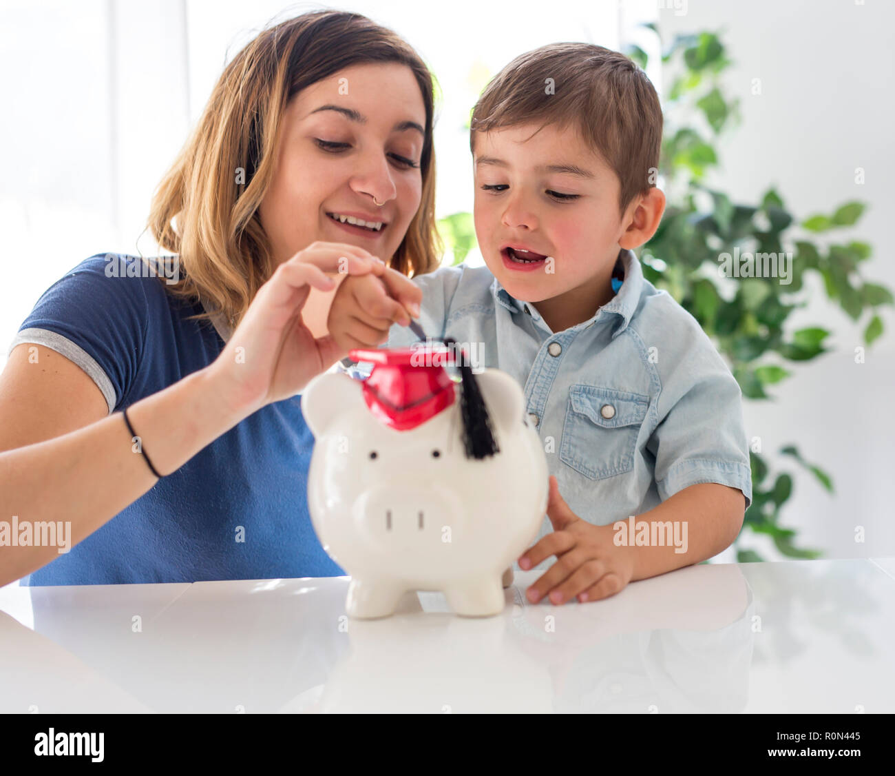 A Little boy and his mother inserting money into piggy bank. Mother ...