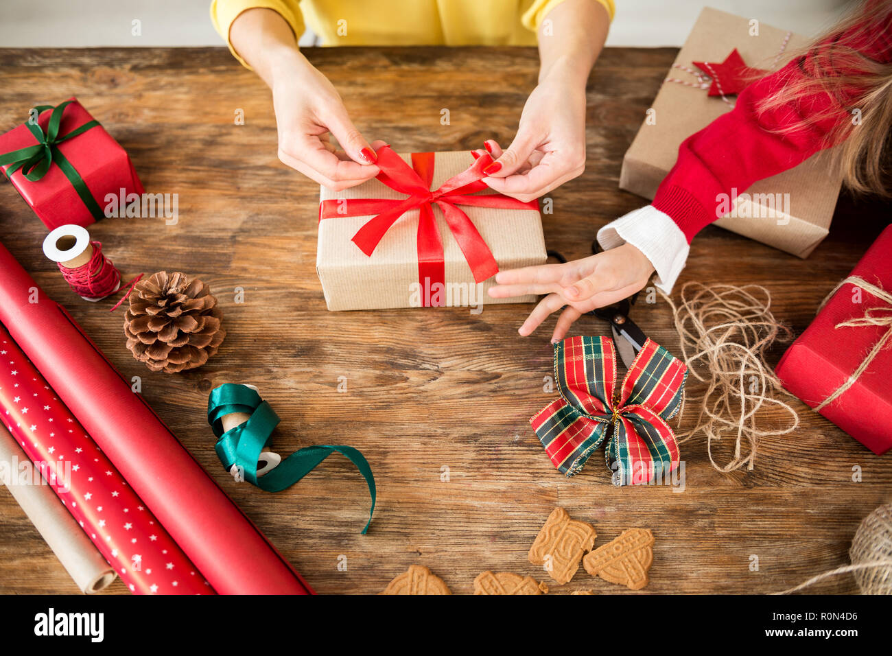 Mother wrapping christmas gifts. Cheeky daughter trying to steal ...