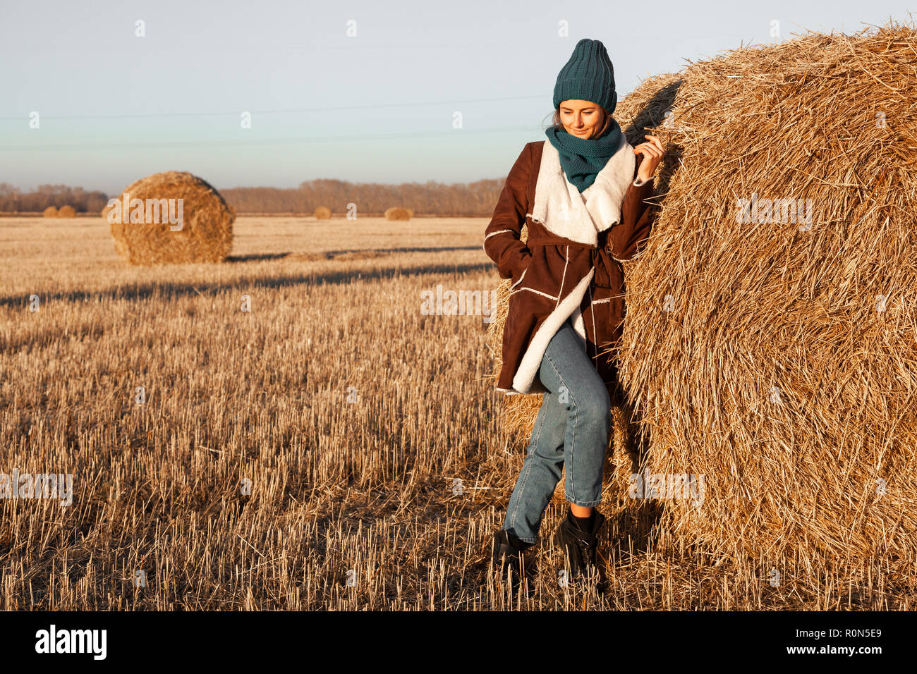 Young attractive lady in blue knitting hat and brown coat stay under ...