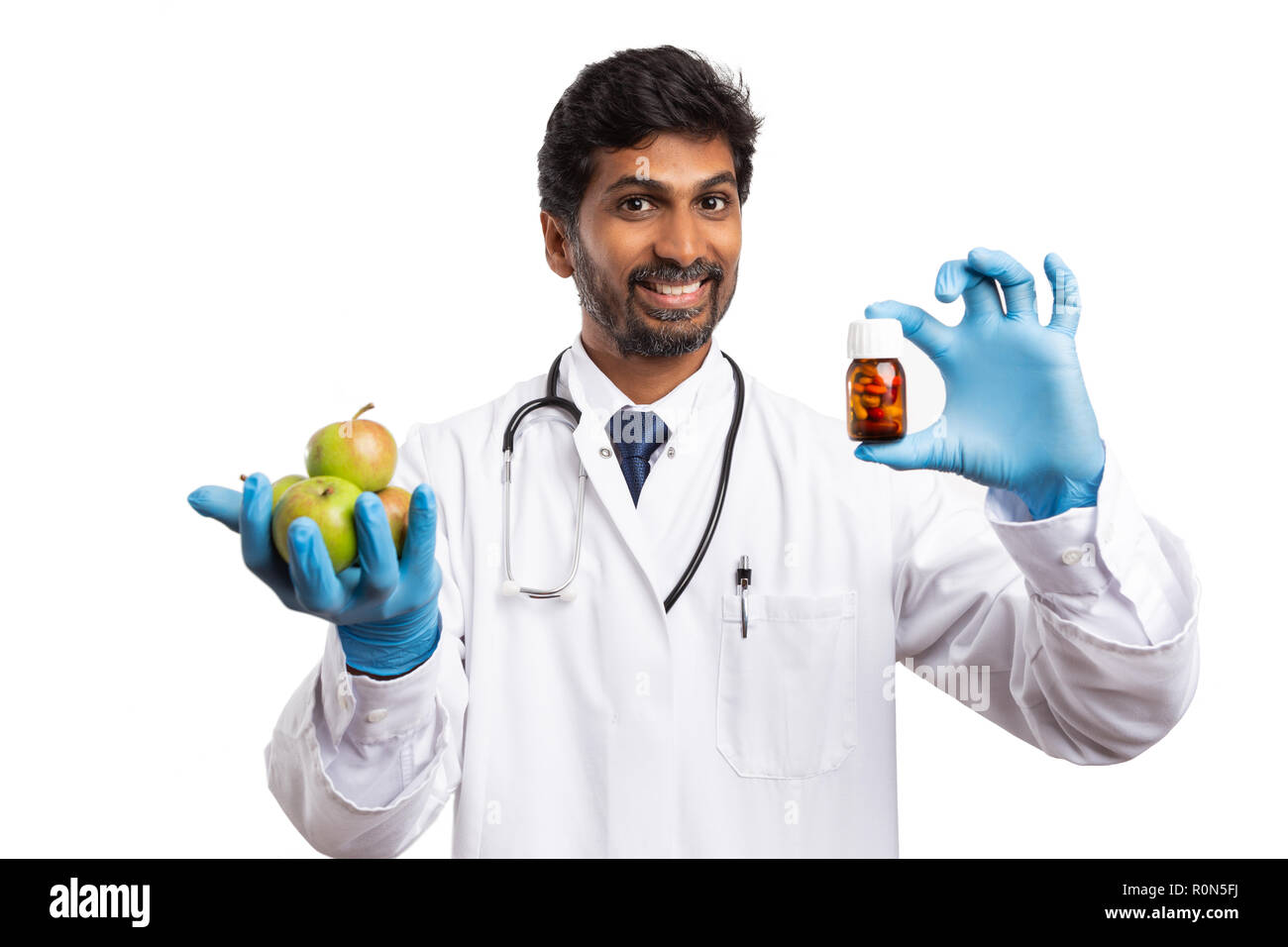 Indian medic man with friendly expression presenting apples and drug ...