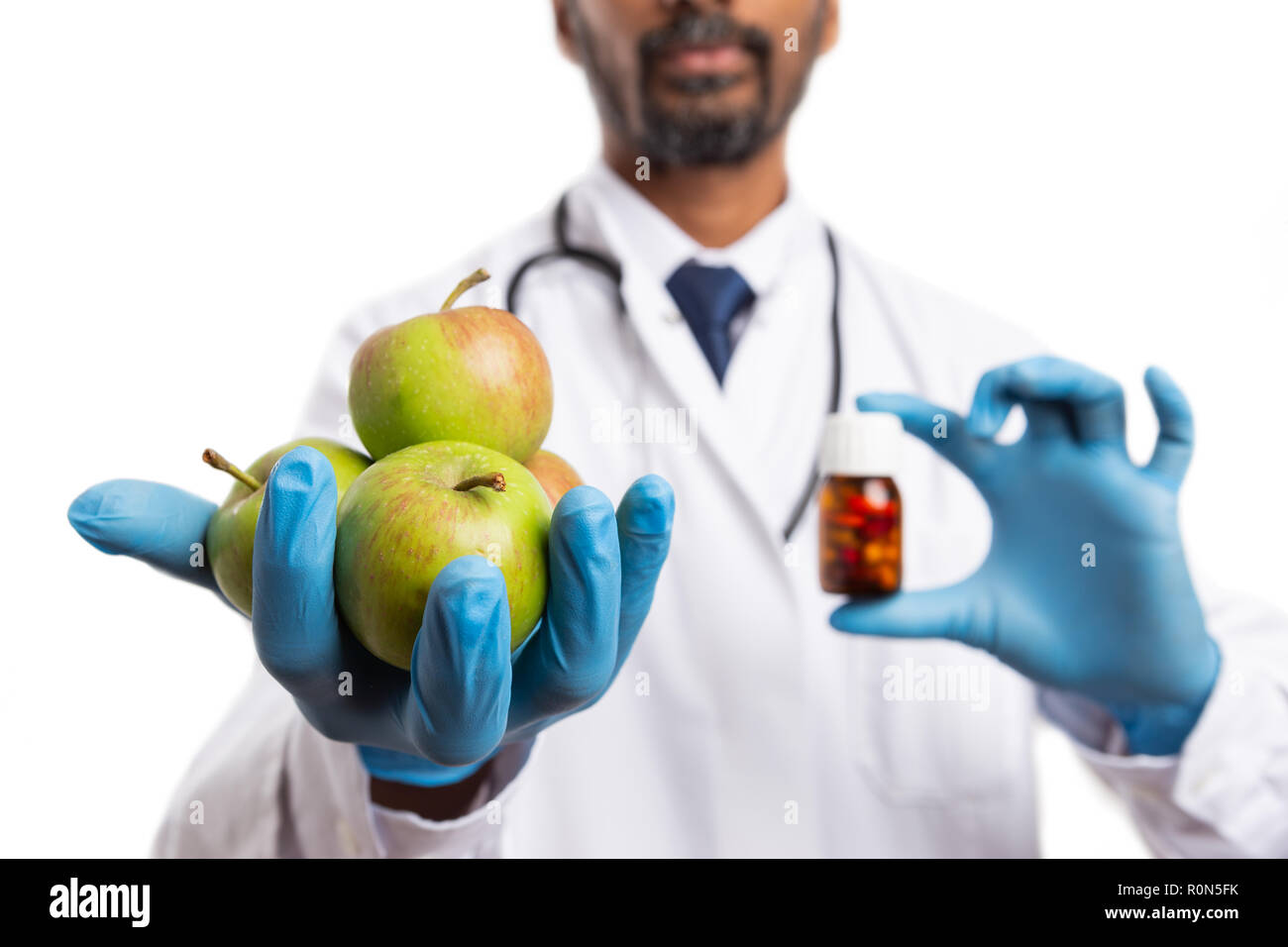 Green apples held by indian medic while having bottle with diet pills ...
