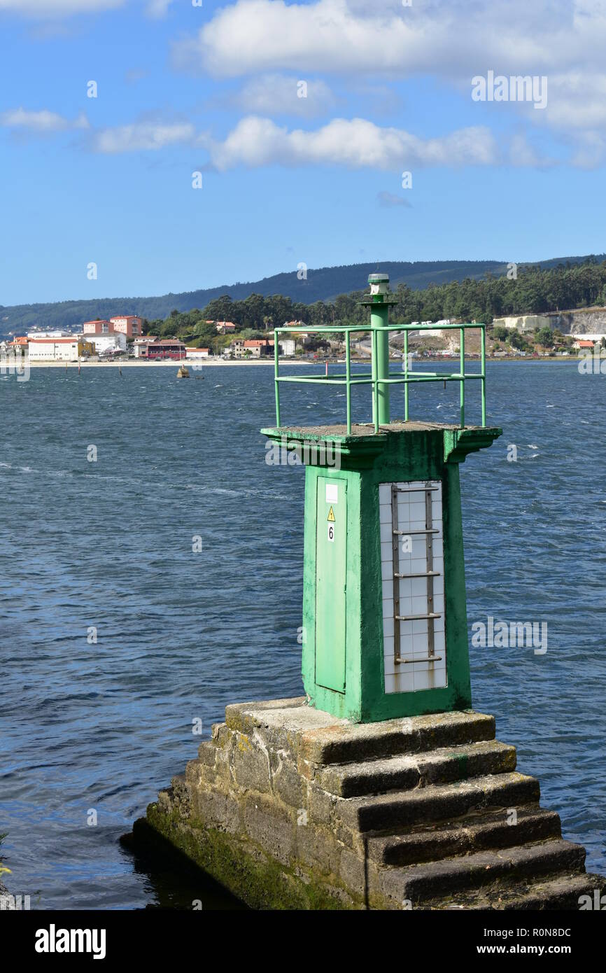 Small green lighthouse in a bay. Small coastal village, blue water ...