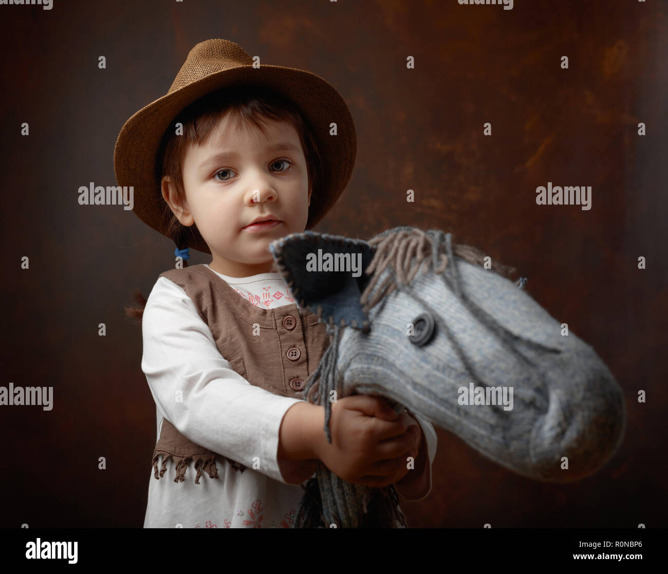 Portrait of little girl dressed like a cowboy playing with a homemade ...