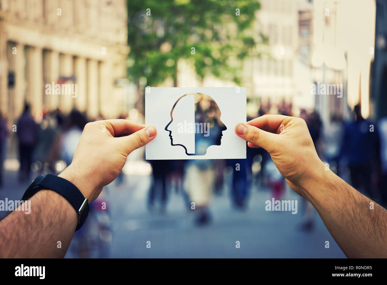 Man hands holding a white paper sheet with two faced head over a ...