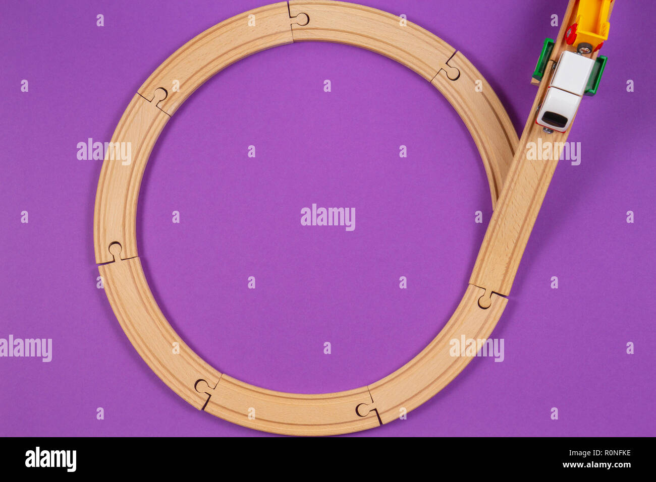 Toy train and wooden rails on purple violet background Stock Photo - Alamy