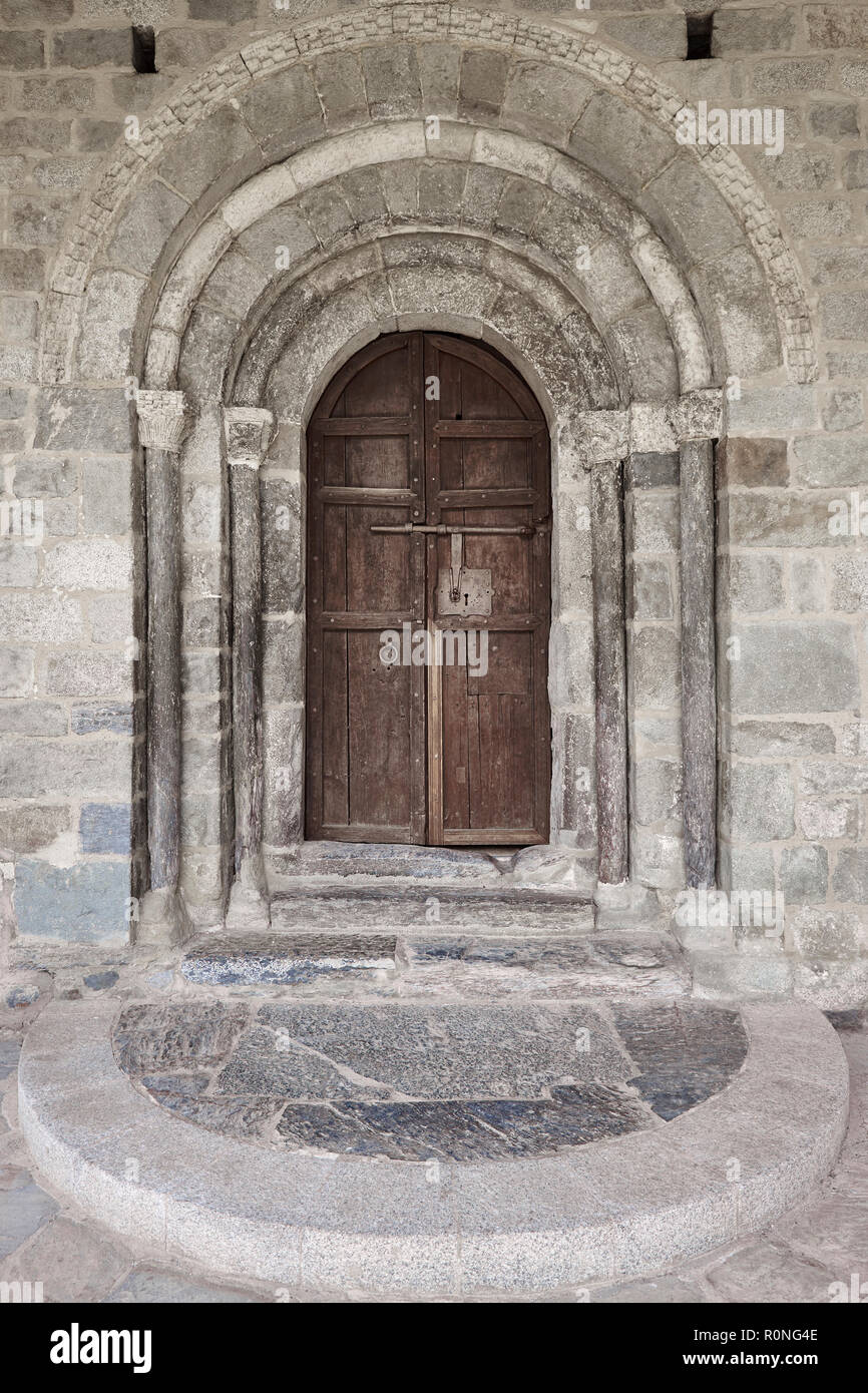 Romanesque entrance arch and capital with antique wooden door. Spain ...