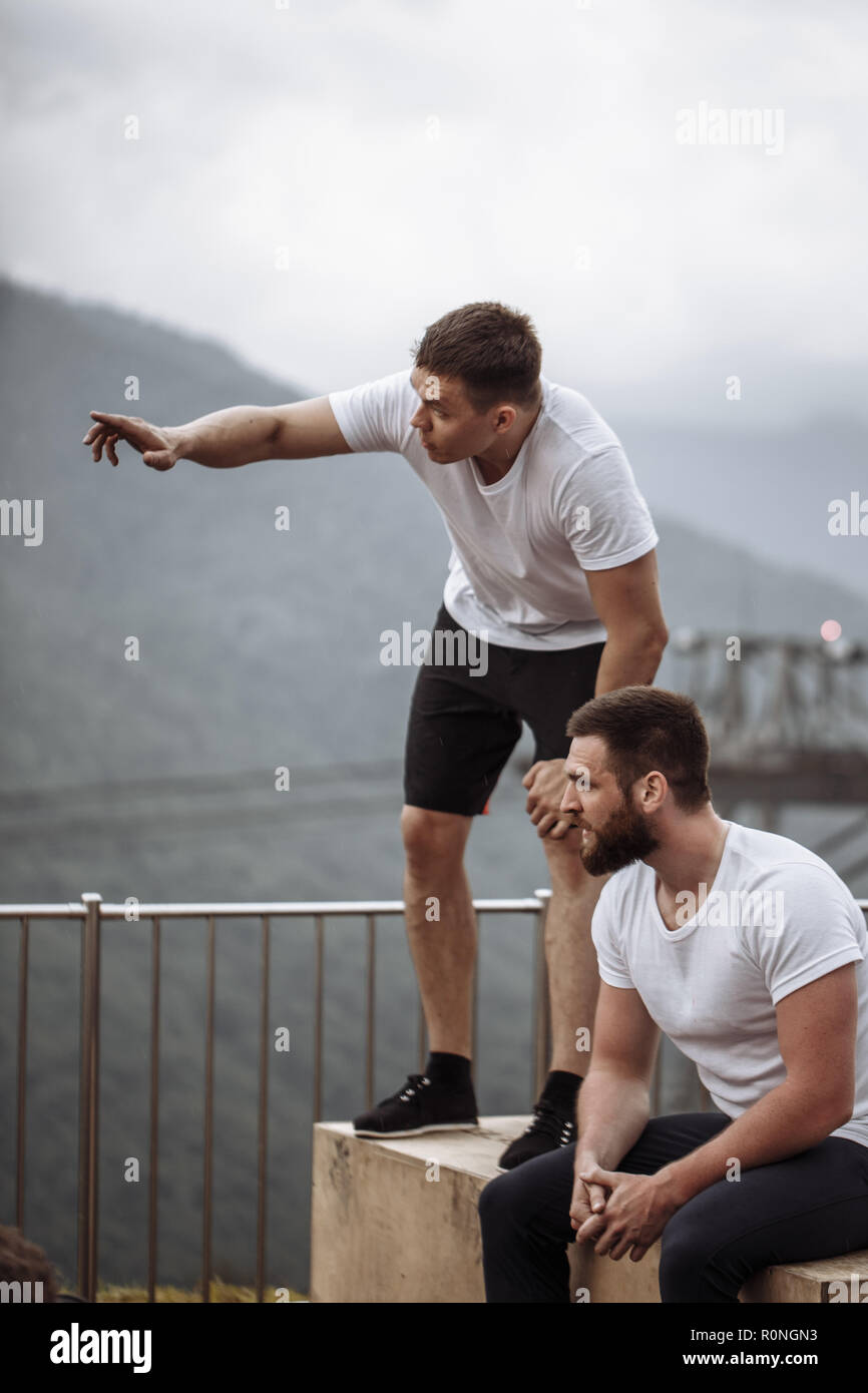 Two athletes rest after intense outdoor workout training in mountain ...