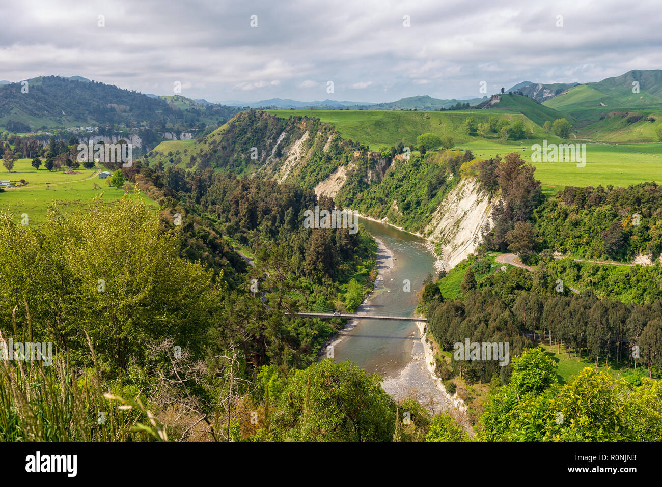 A bridge spanning a river flowing in a deep gorge in a lush countryside ...