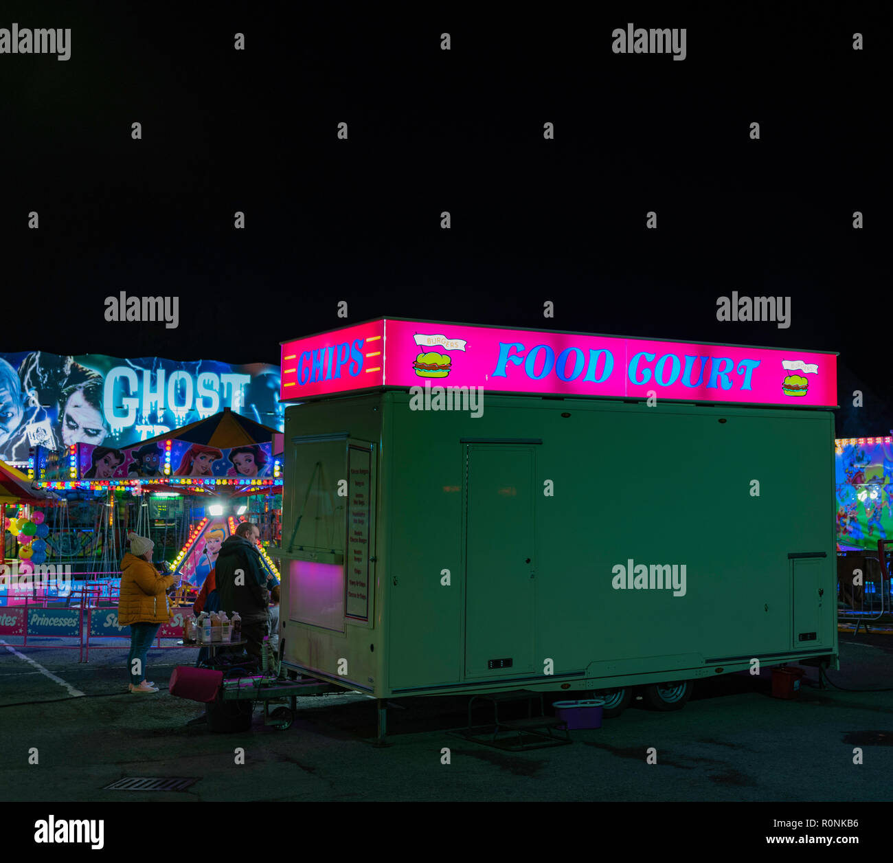 A neon-lit fast food trailer in a fun fair in Machynlleth, Wales, UK ...