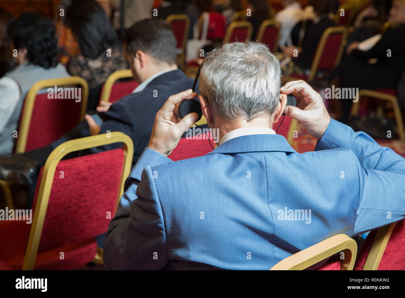 Unrecognizable business people using headphones for translation during ...