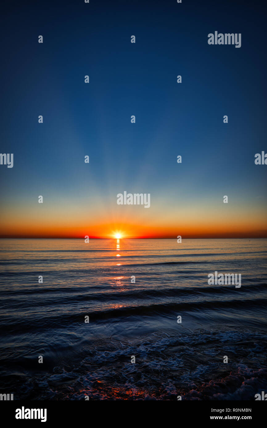A vertical photo of the sun rising over the Mediterranean with deep ...