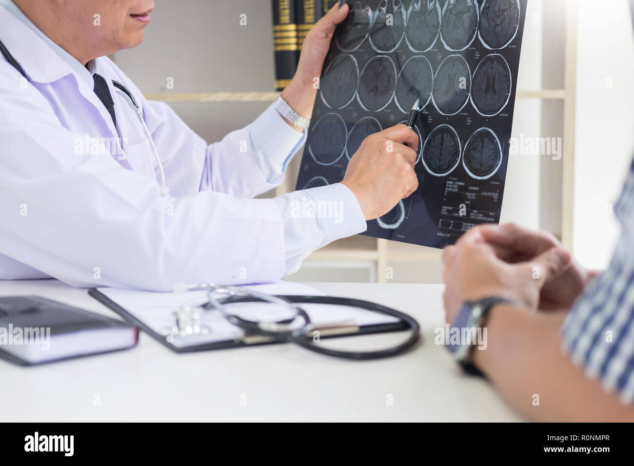 doctor analyzing a scan or x-ray film or explains a CT scan thoughtful ...