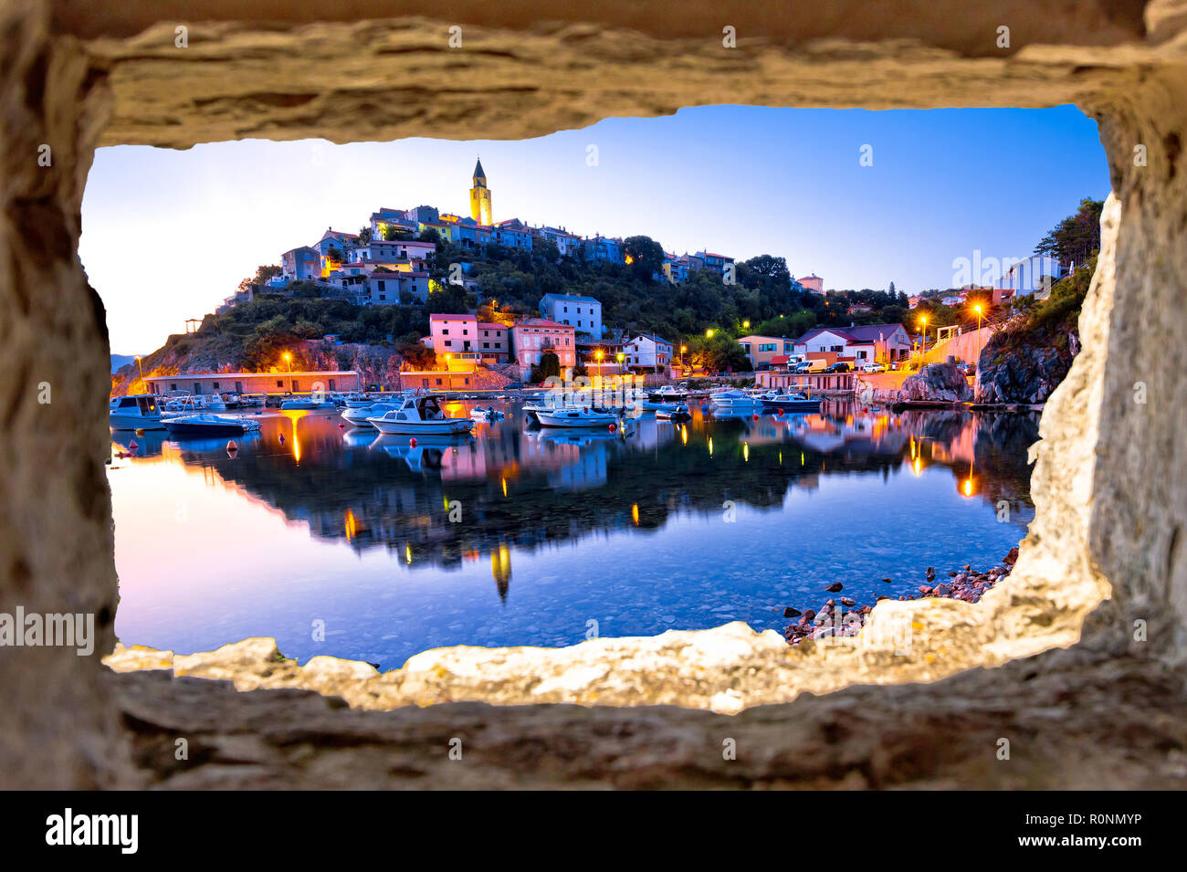 Town of Vrbnik harbor view morning glow view through stone window ...