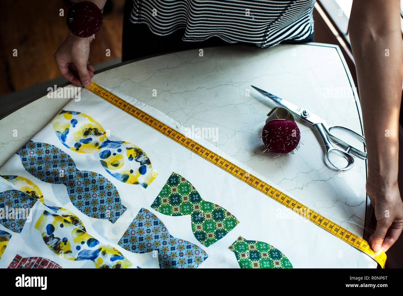 High angle close up of fashion designer working in studio, measuring ...