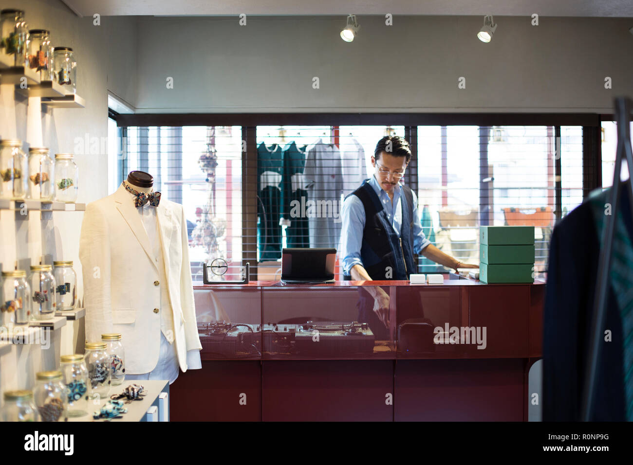 Japanese salesman with moustache wearing glasses standing at counter in ...
