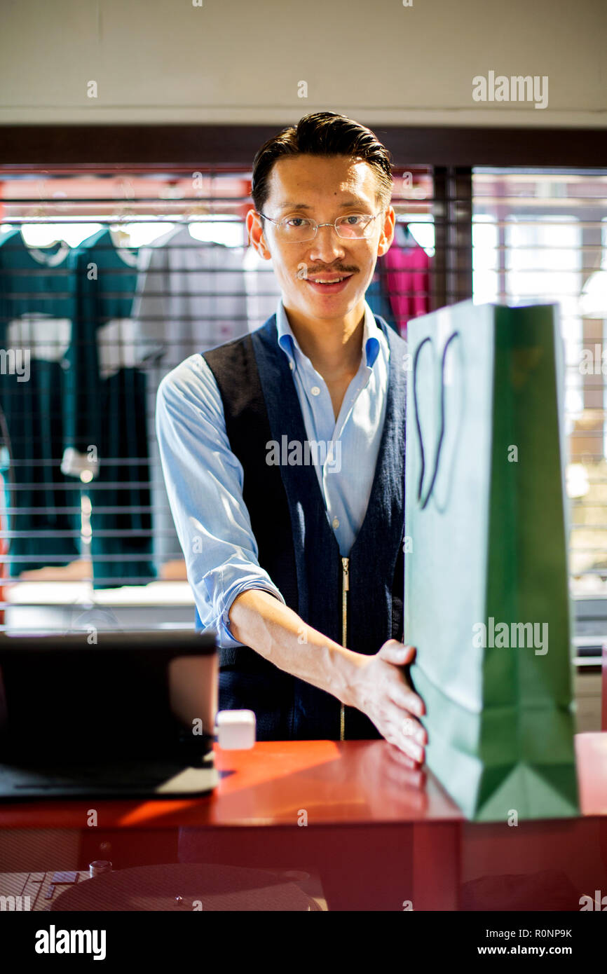 Japanese salesman with moustache wearing glasses standing at counter in ...