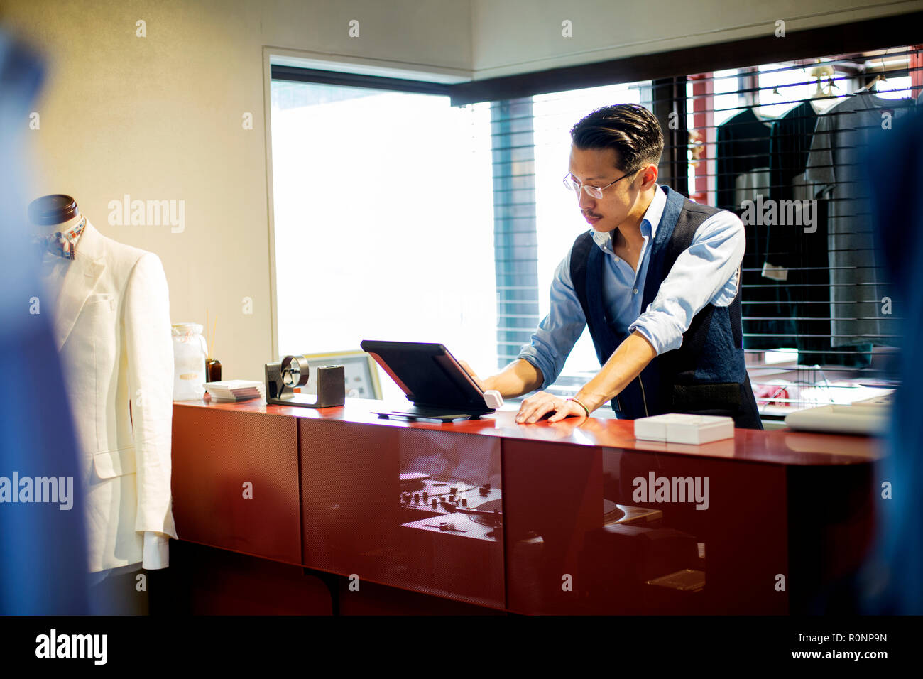 Japanese salesman with moustache wearing glasses standing at counter in ...