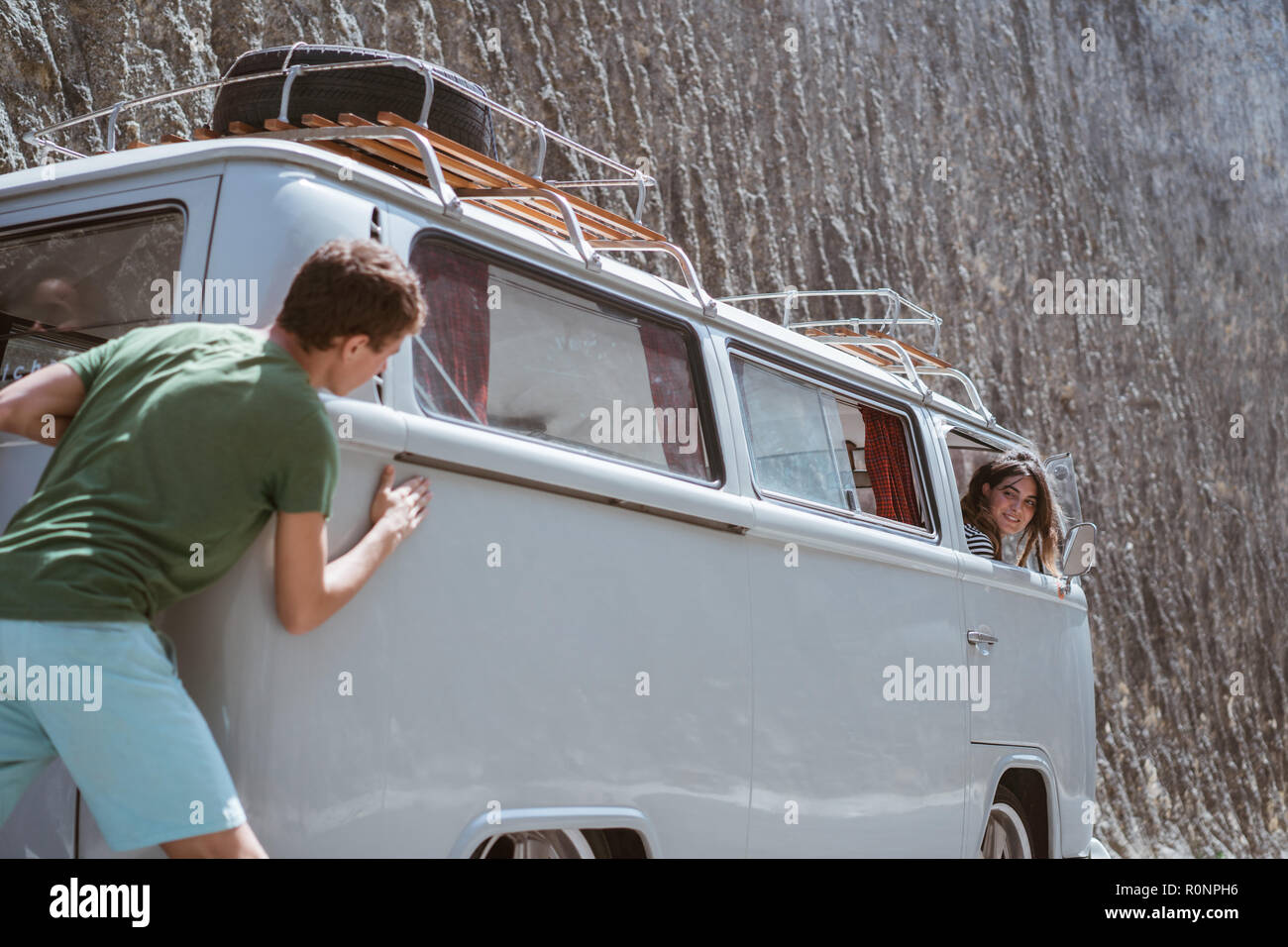 portrait a man push broke down retro van Stock Photo - Alamy