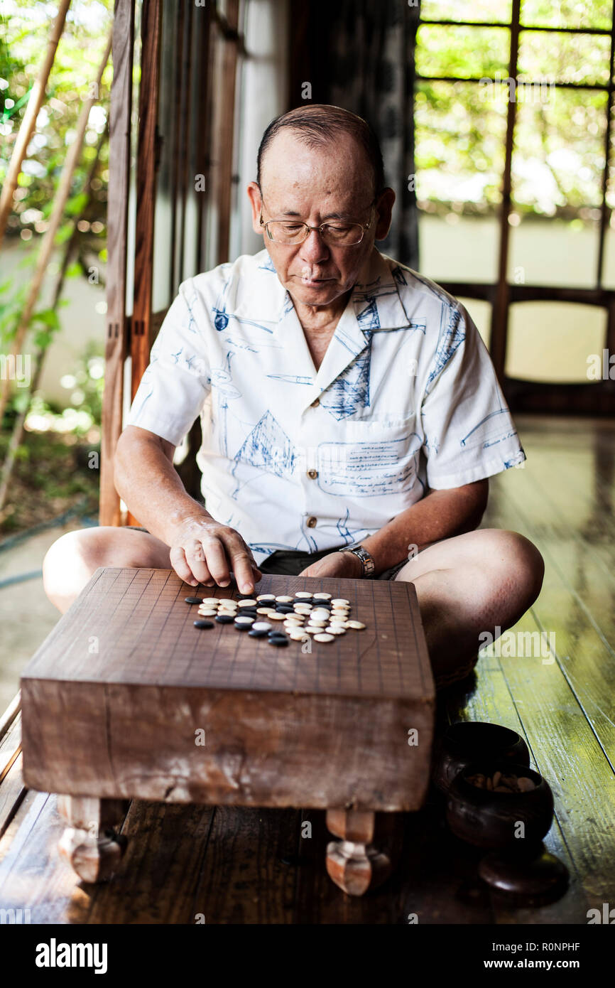 Japanese man sitting on floor on porch of traditional Japanese house ...