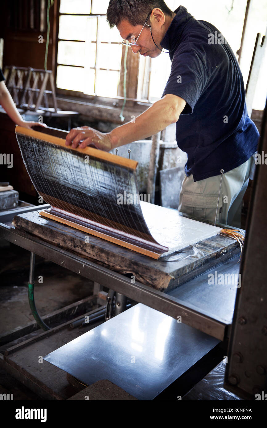 Japanese man holding a paper frame and inspecting fresh piece of ...