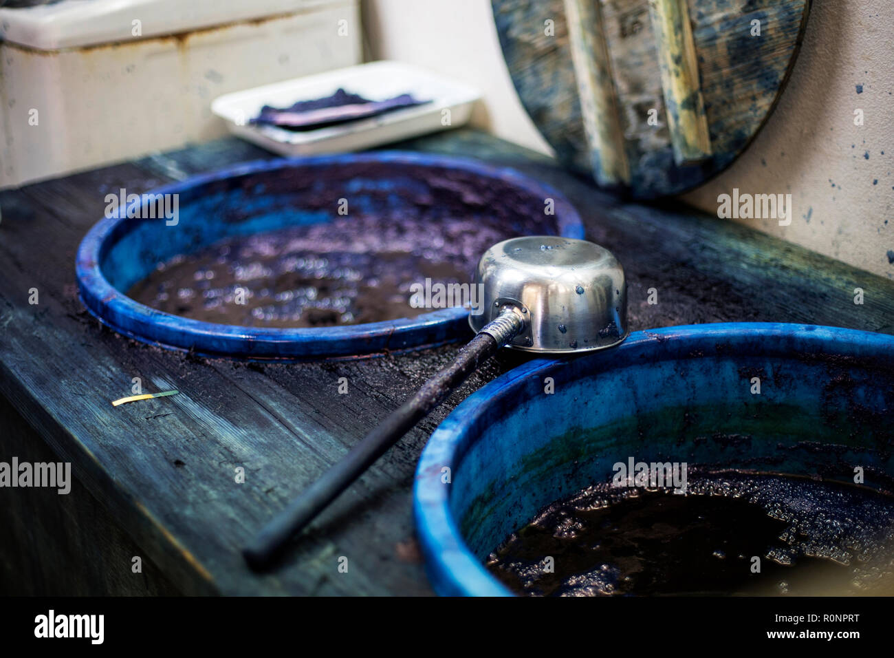 High angle close up of ladle and buckets with blue dye in a textile ...