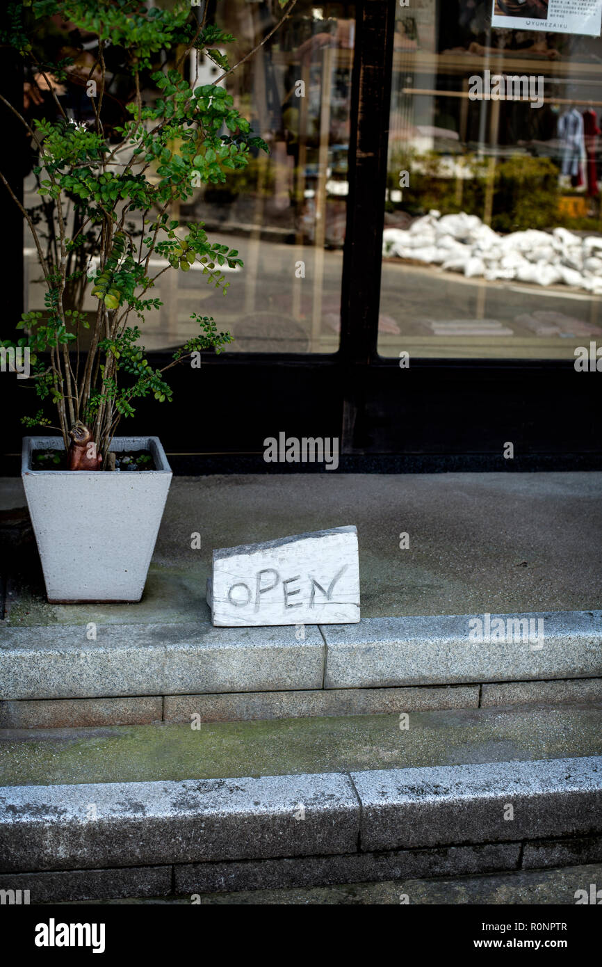 An Open sign and plant pot on steps in front of a store entrance Stock ...