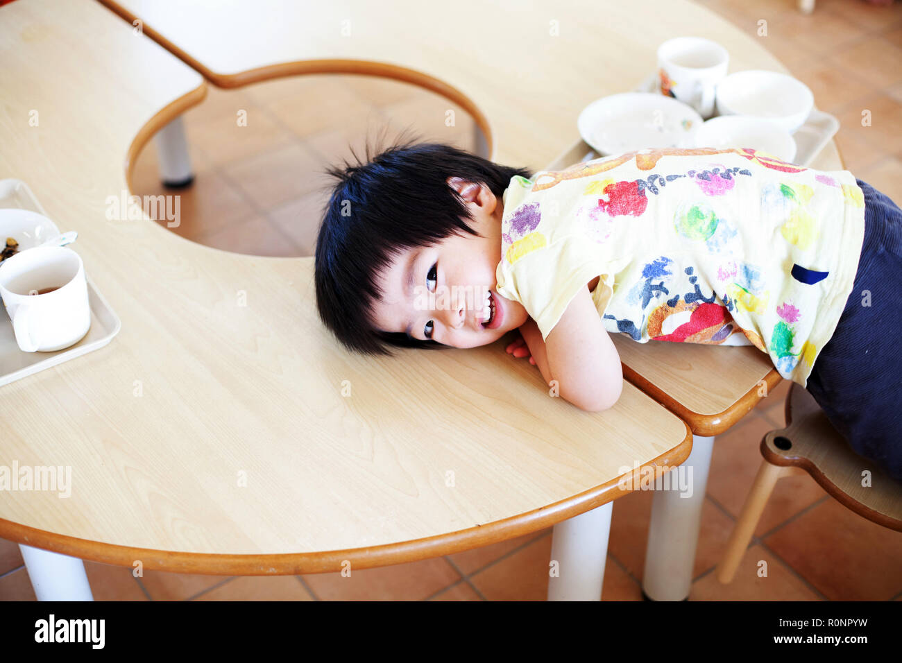 High angle view of a young boy lying on table looking up, in a Japanese ...