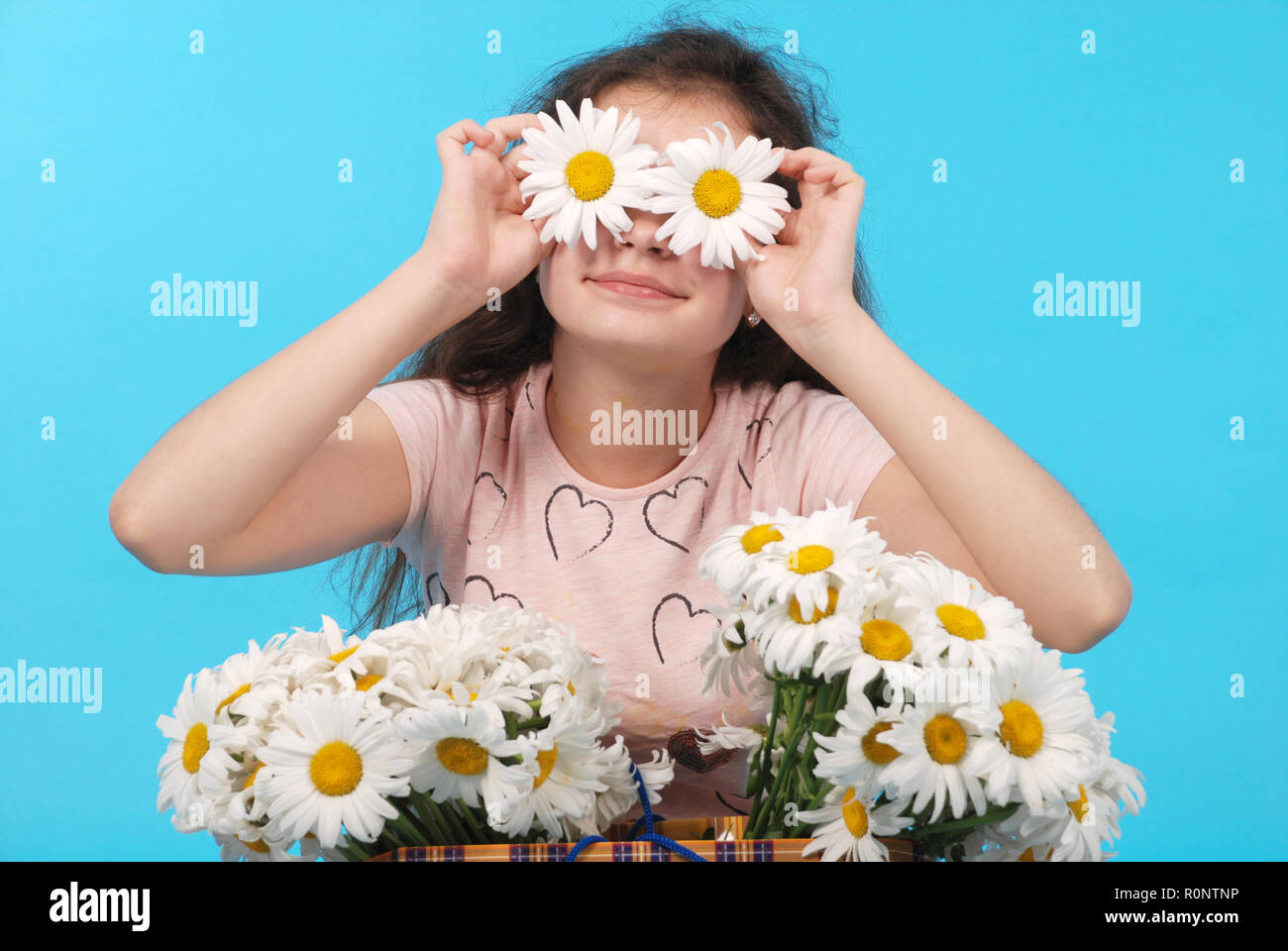 Beautiful young girl with daisy eyes on blue background Stock Photo - Alamy
