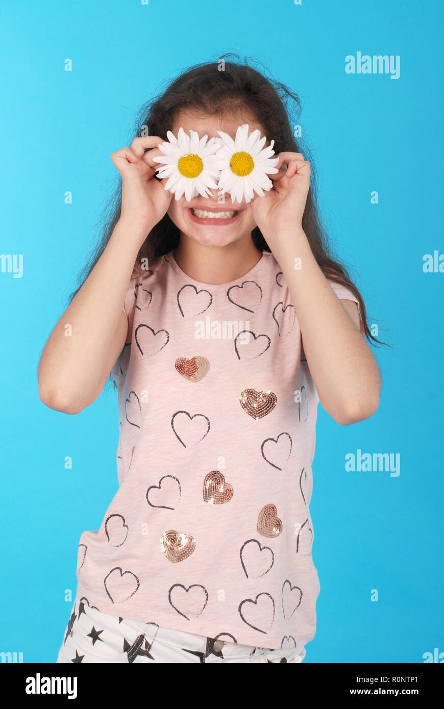 Beautiful young girl with daisy eyes on blue background Stock Photo - Alamy