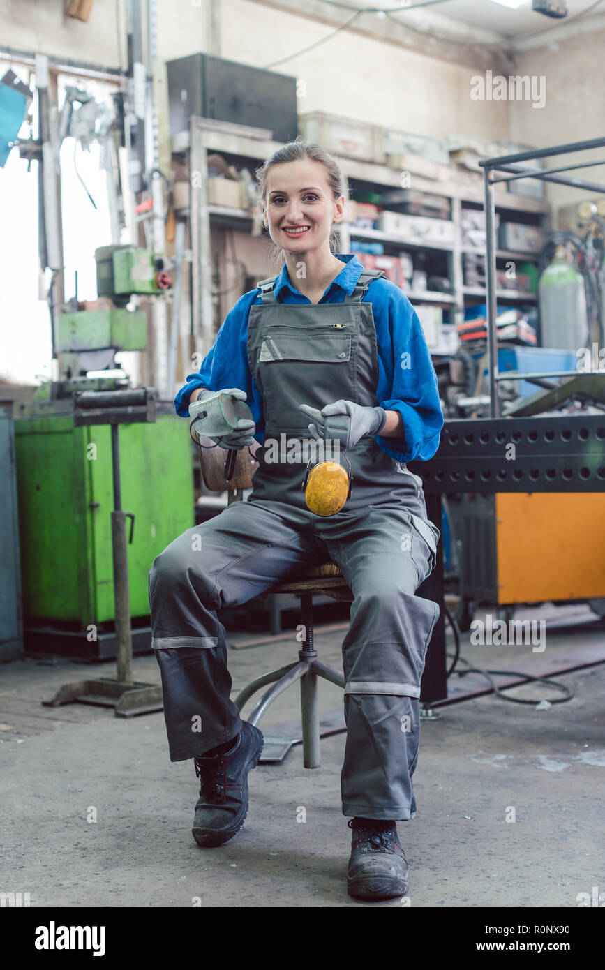 Female mechanic sitting in metal workshop looking into camera Stock ...