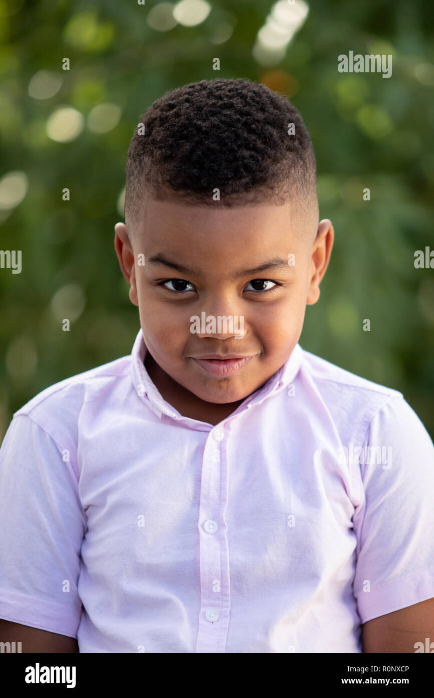 Adorable latin child in the garden with a beautiful green of background ...