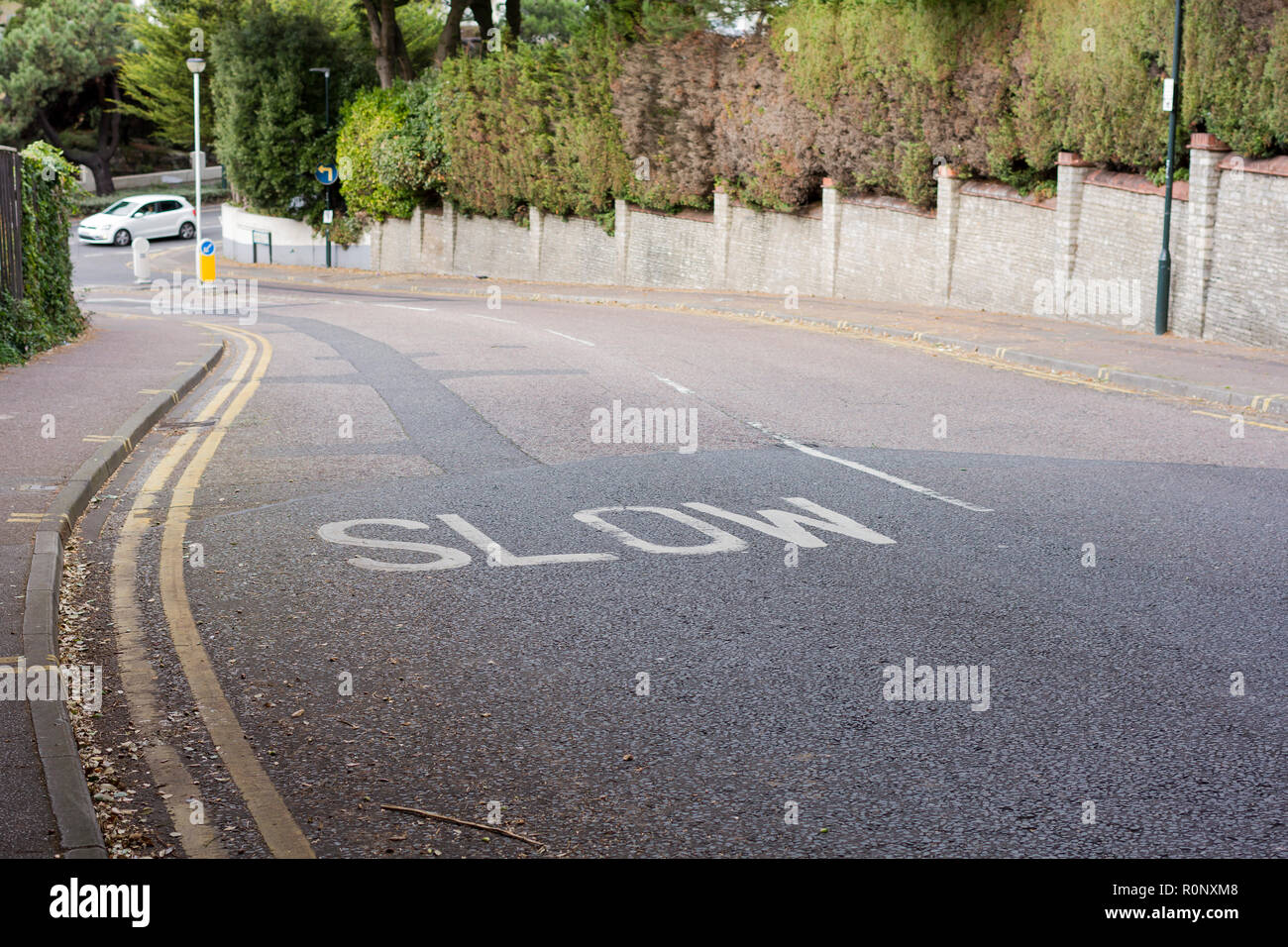 Slow warning sign painted in white on road surface, next to double ...