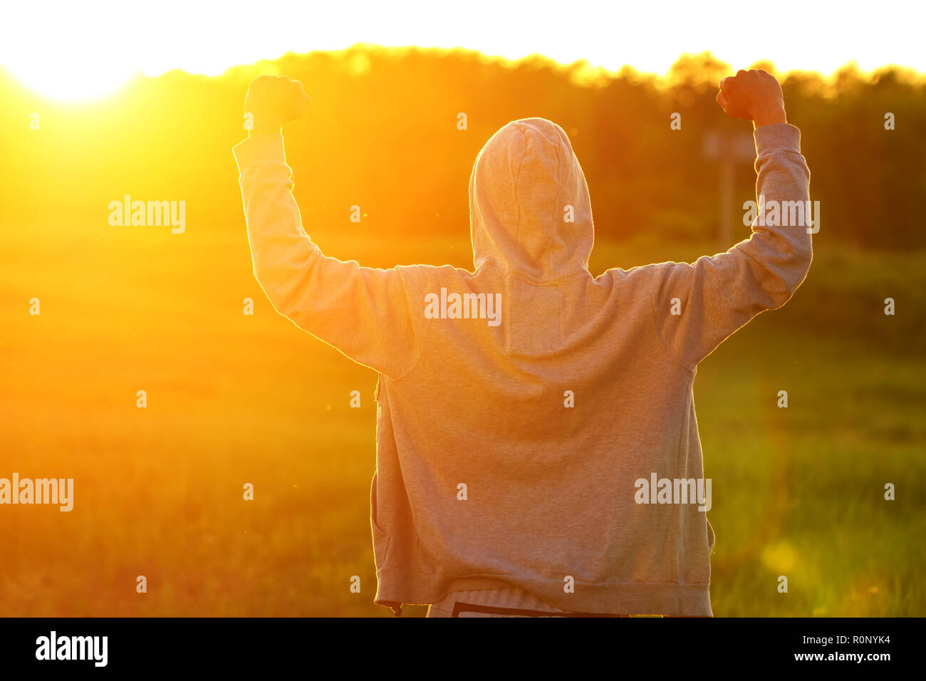 a man in the light of the sunset with his hands up, the concept of ...