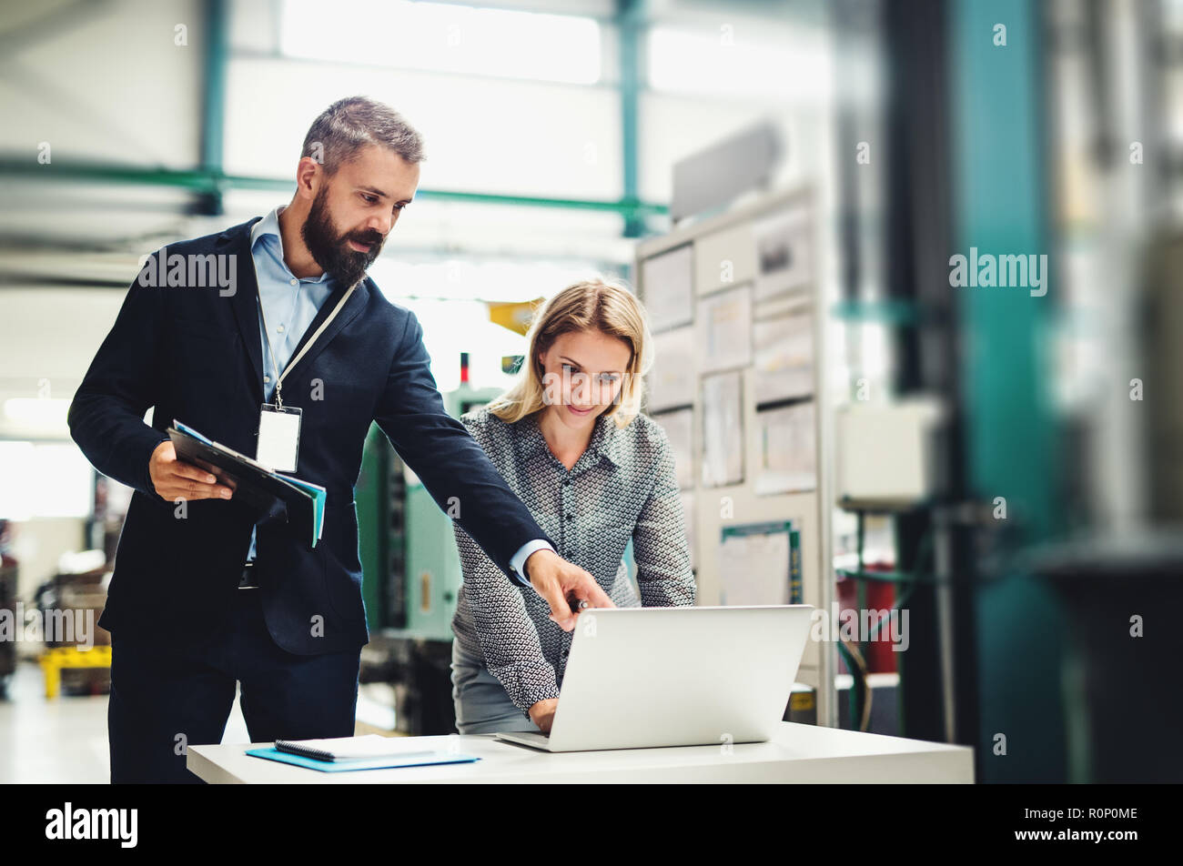 A portrait of an industrial man and woman engineer with laptop in a ...