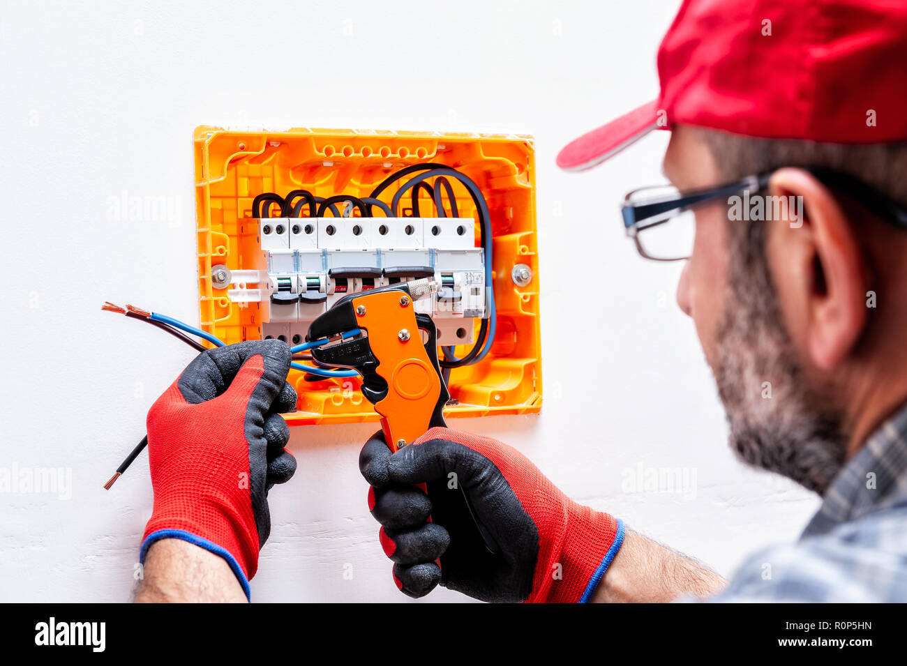Electrician technician with glove-protected hands, works with the wire ...